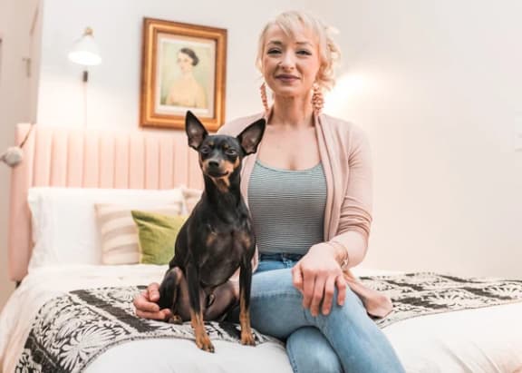 a woman sitting on a bed with her dog